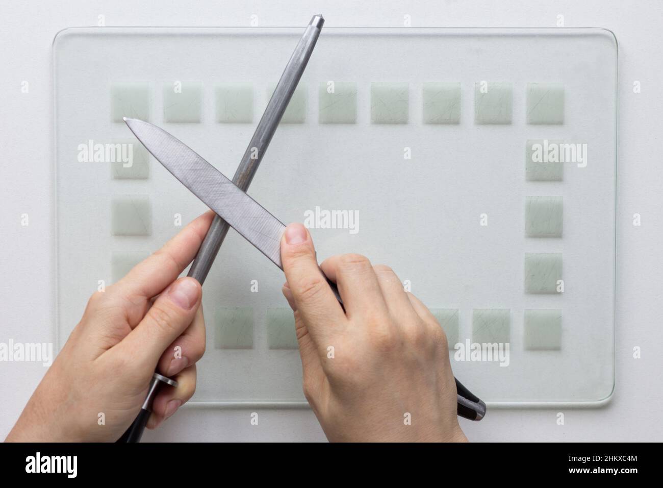 Knife and sharpener in woman hands sharpening on the white background ...