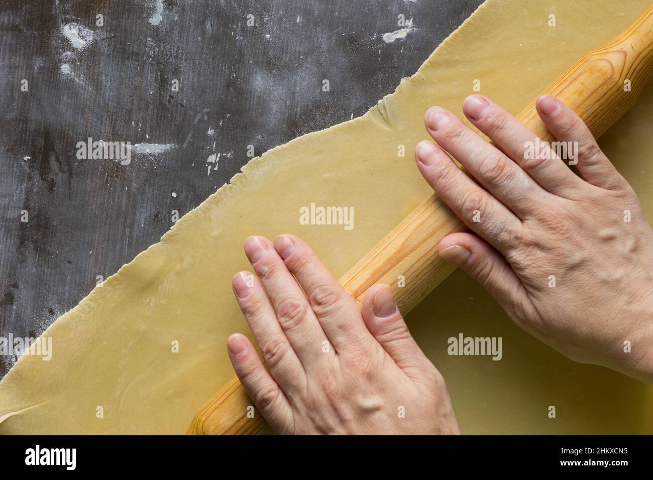Woman hands rolling dough for noodles by rolling pin on the powdered by ...