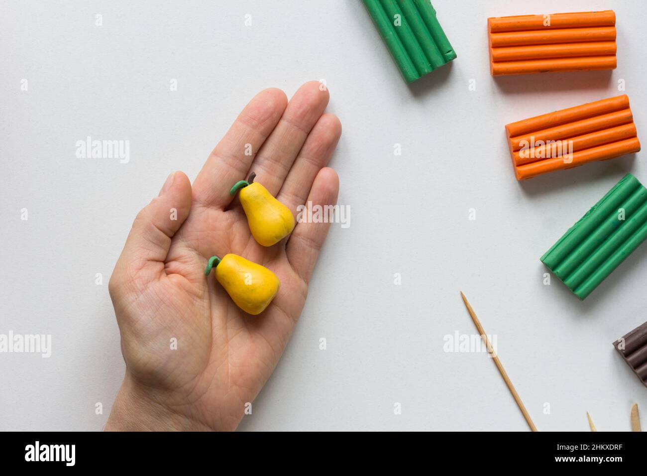Two handmade small pears made from polymer clay on woman hand on the ...