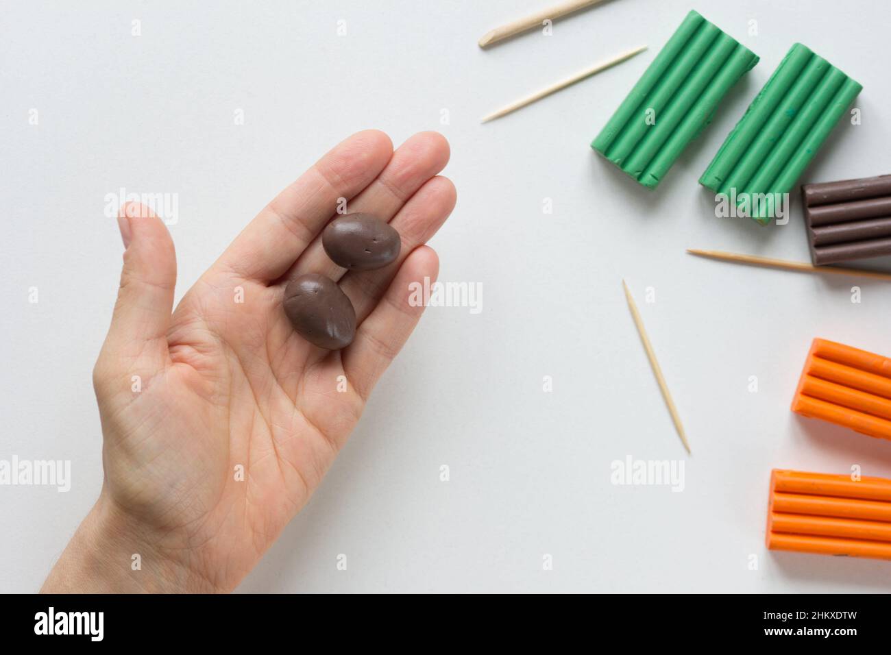 Two handmade small potatoes made from polymer clay on woman hand on the ...