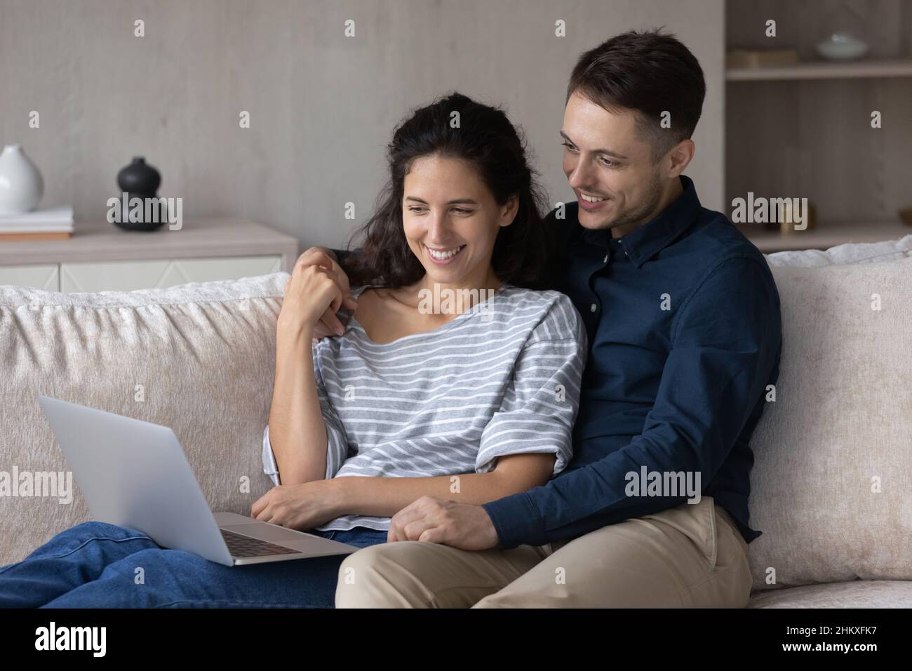 Happy couple using laptop together, relaxing on couch Stock Photo - Alamy