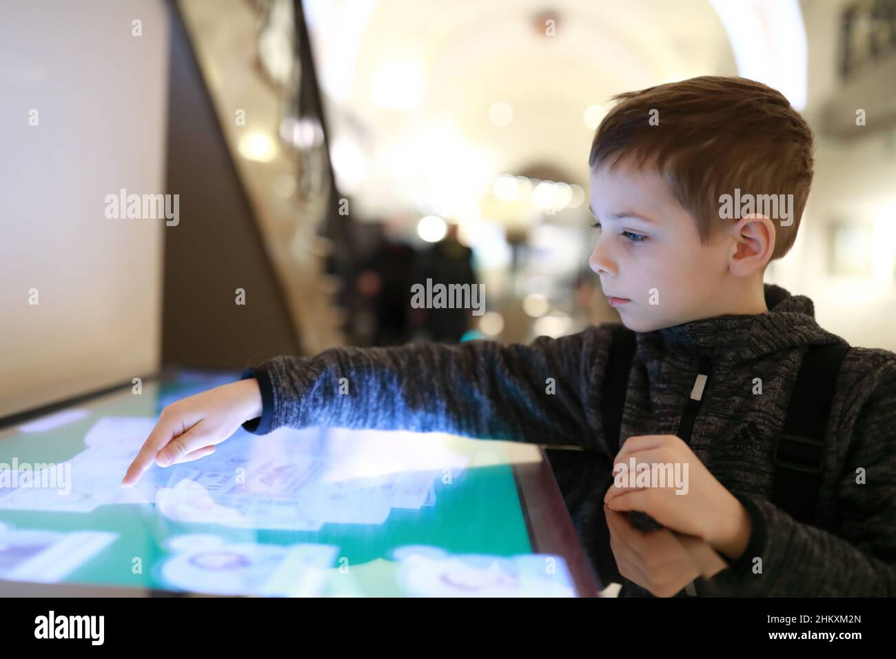 Portrait of kid playing puzzles on touch screen in entertainment center ...