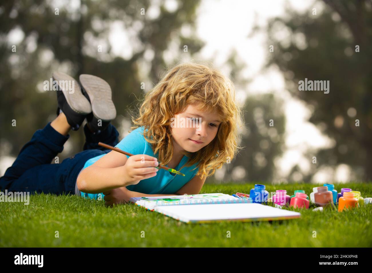 Child boy enjoying art and craft drawing in backyard or spring park ...