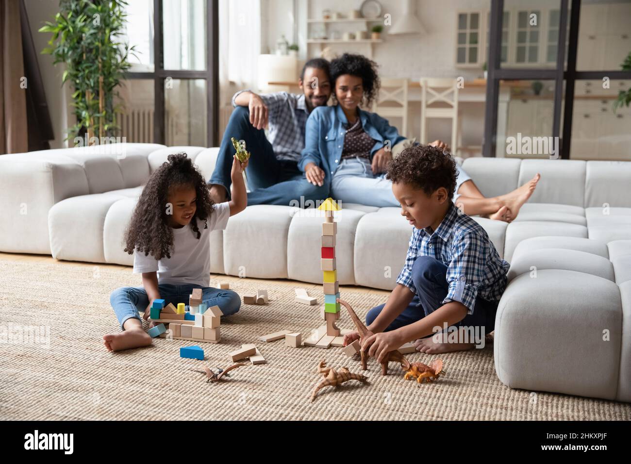 Happy African parents watching little kids playing toys Stock Photo - Alamy