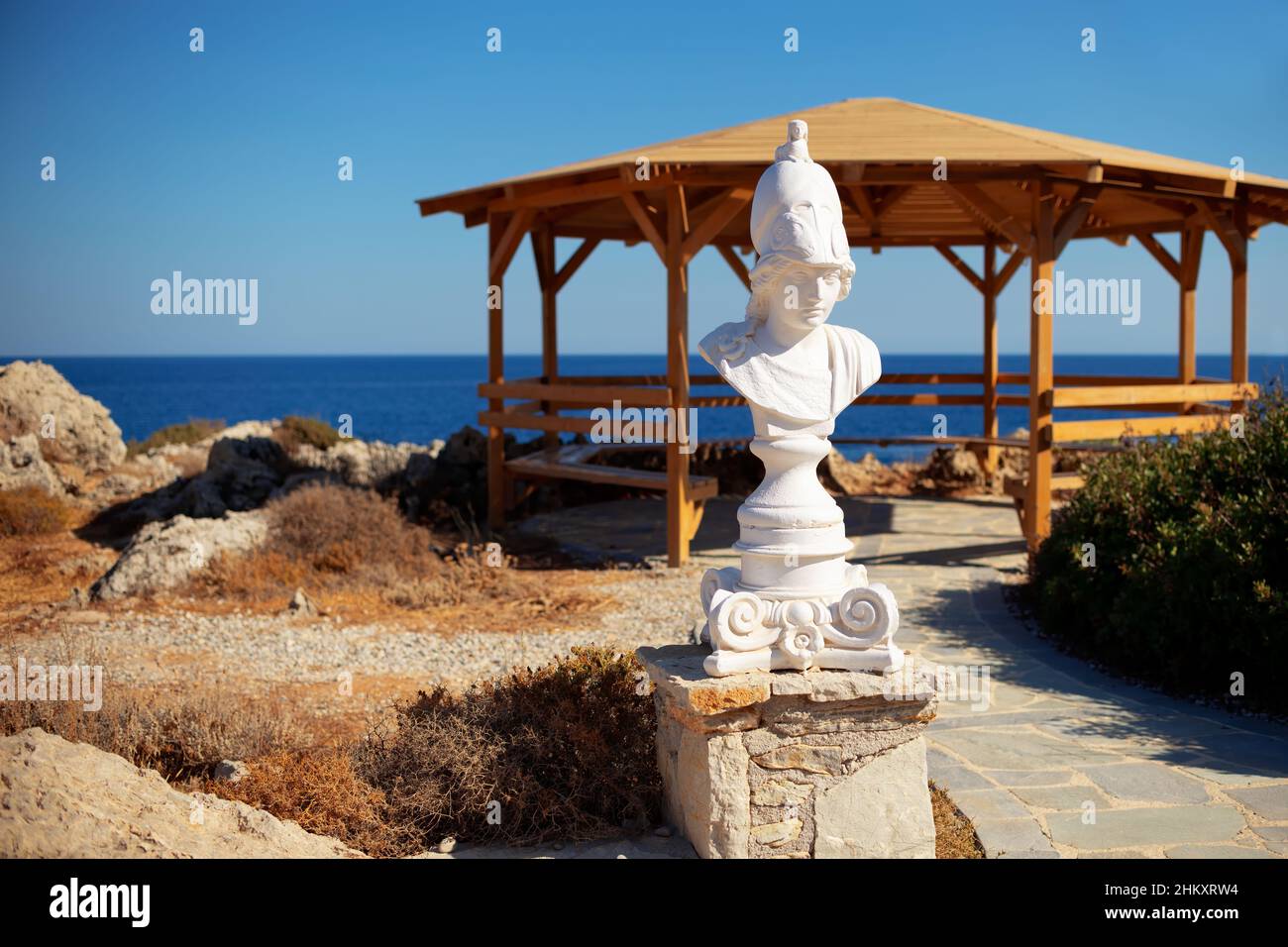 White statue of Greek hero with a view of summer house blue sea and sky ...