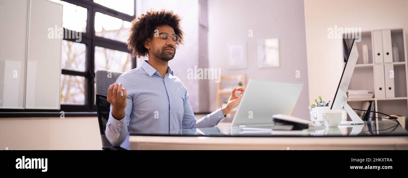 African American Male Meditation In Office Near Computer Stock Photo ...