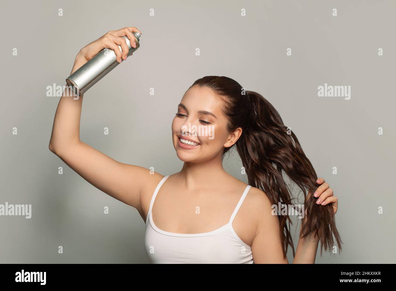 Beautiful young woman applying hair spray on her hair Stock Photo - Alamy