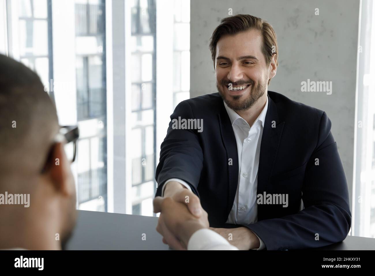Happy business professional man and client shaking hands on meeting ...