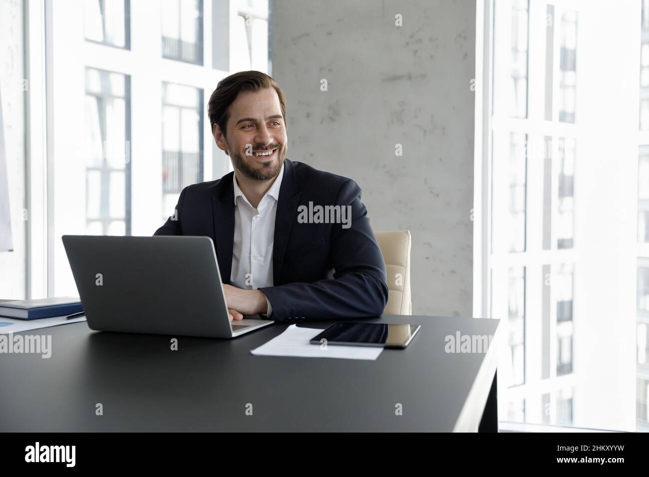 Happy dreamy business professional man working at laptop in office ...