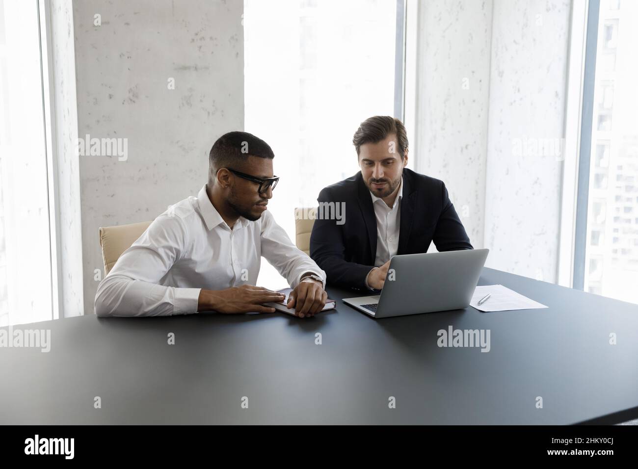 Focused diverse businessmen in formalwear using laptop at office table Stock Photo - Alamy