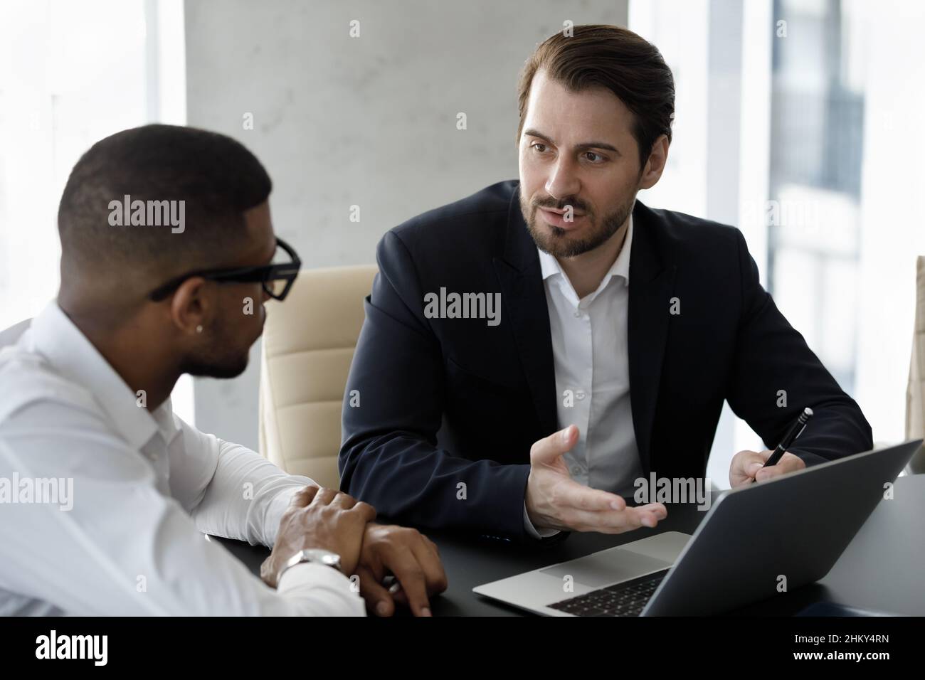 Serious boss, executive, business leader talking to African employee ...