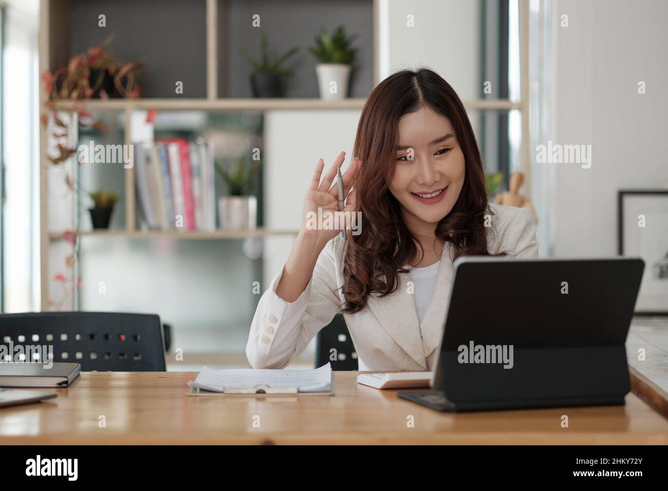 Portrait of smiling asian woman waving hello talking on video call ...