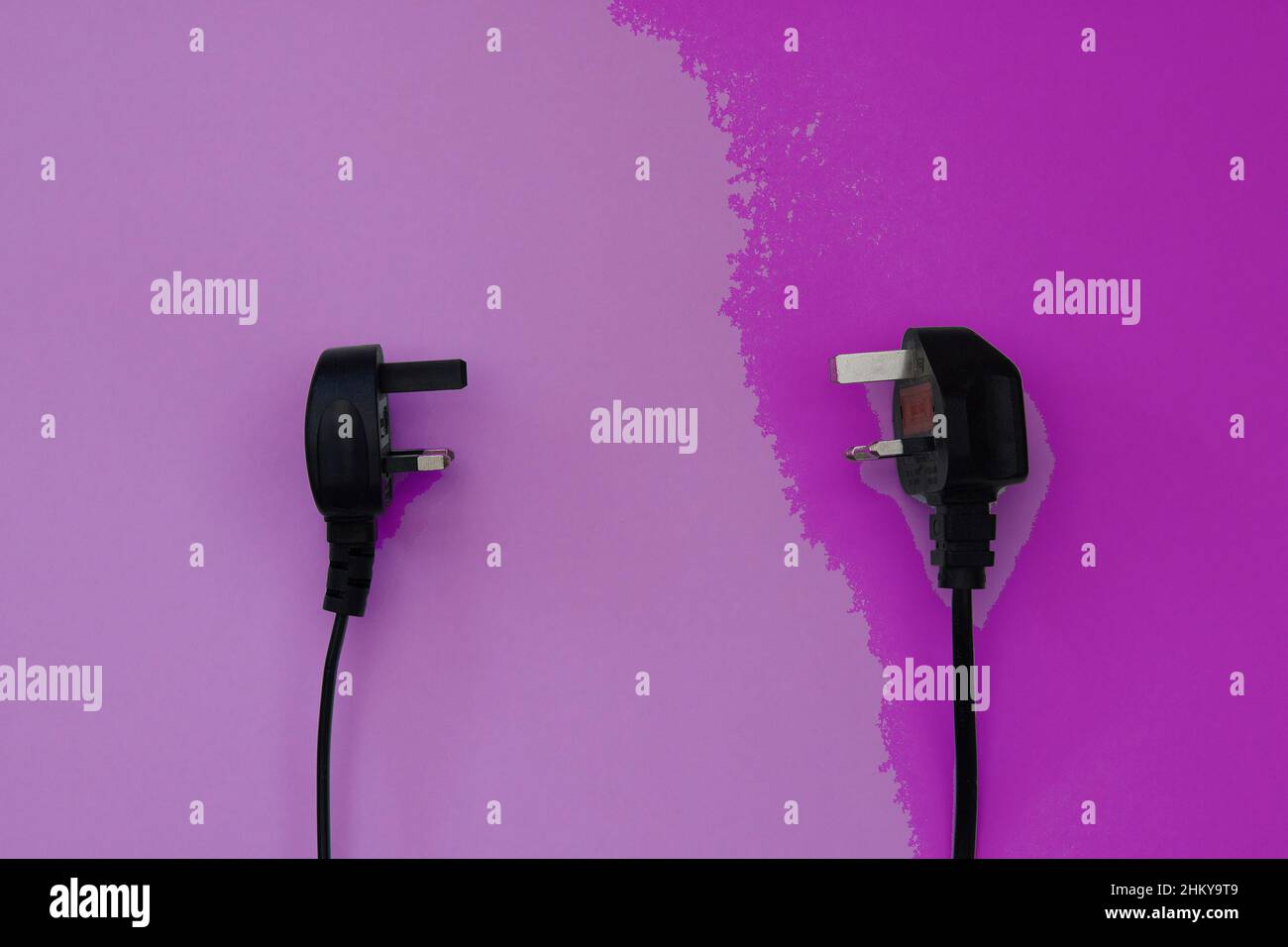 Two electrical plugs seen facing each other on a colourful background ...