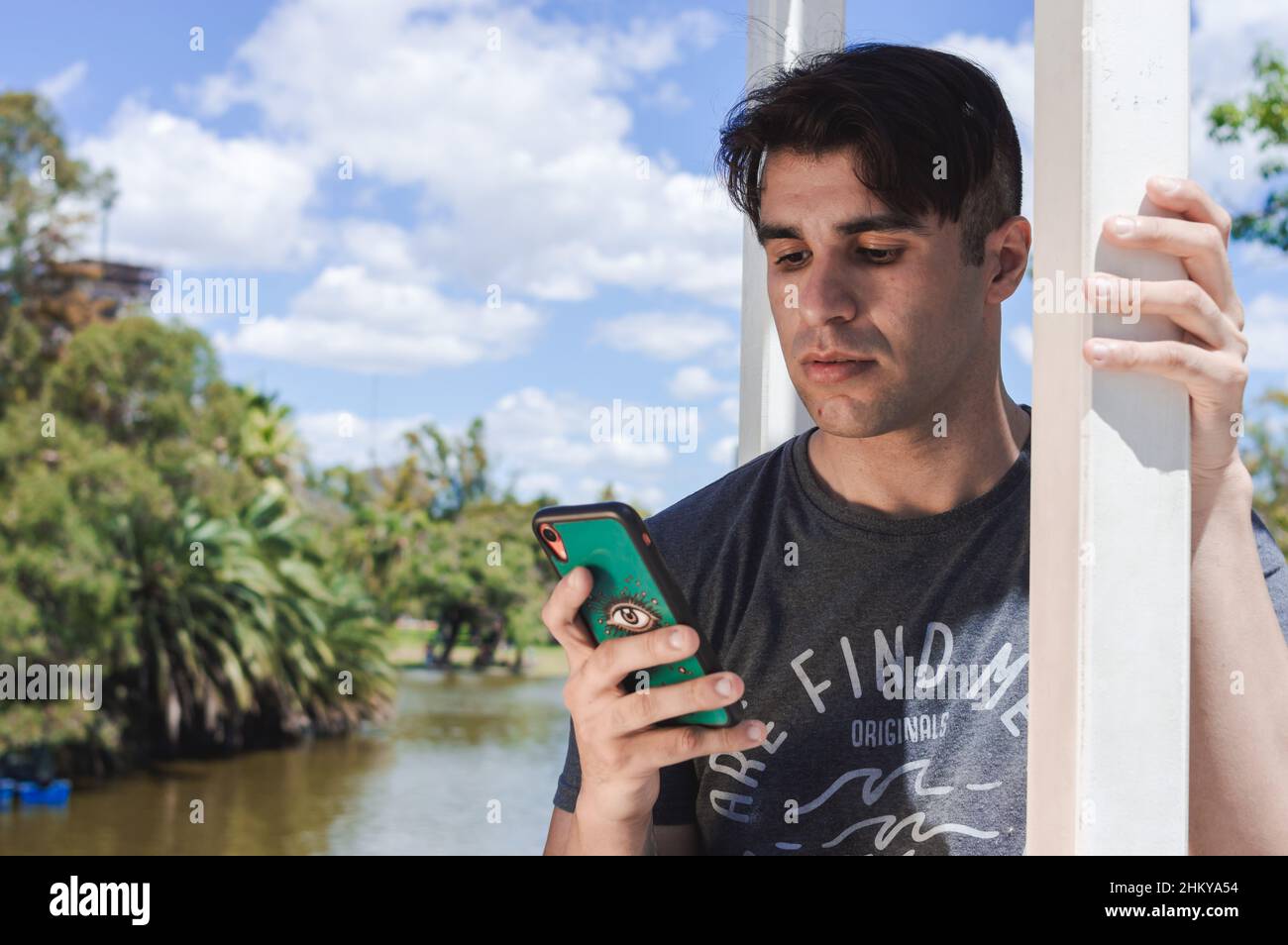 portrait of young caucasian hispanic latin man, sitting on a bridge ...
