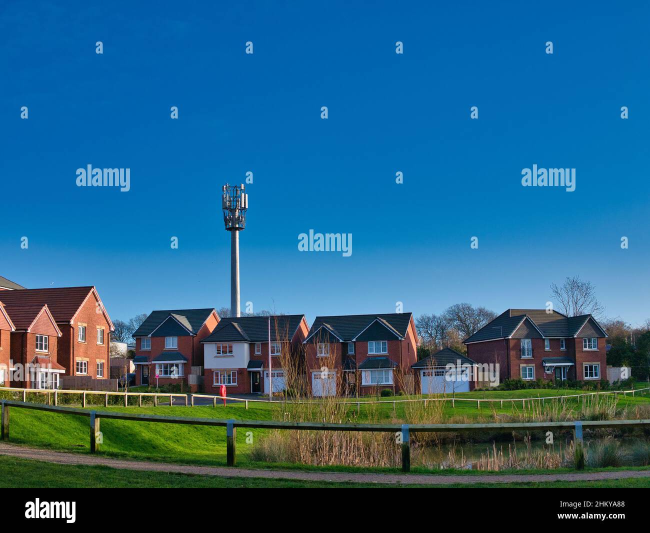 A tall mobile phone mast next to modern residential housing with a ...