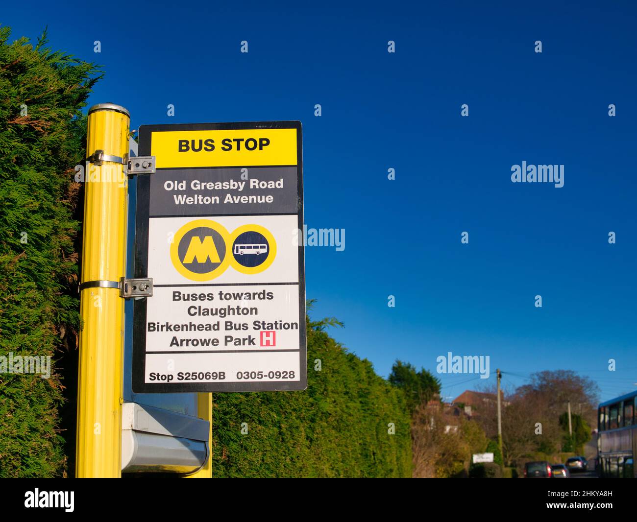 Fixed to a yellow metal post, a local bus stop sign showing location ...