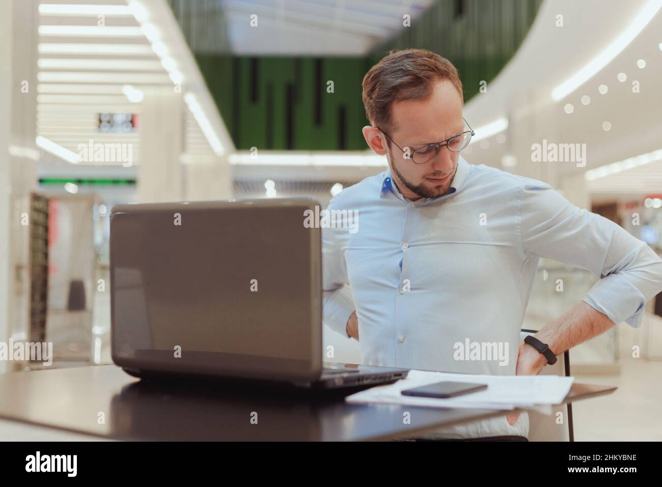 Man holds on to his back, suffers from lower back pain, working on ...
