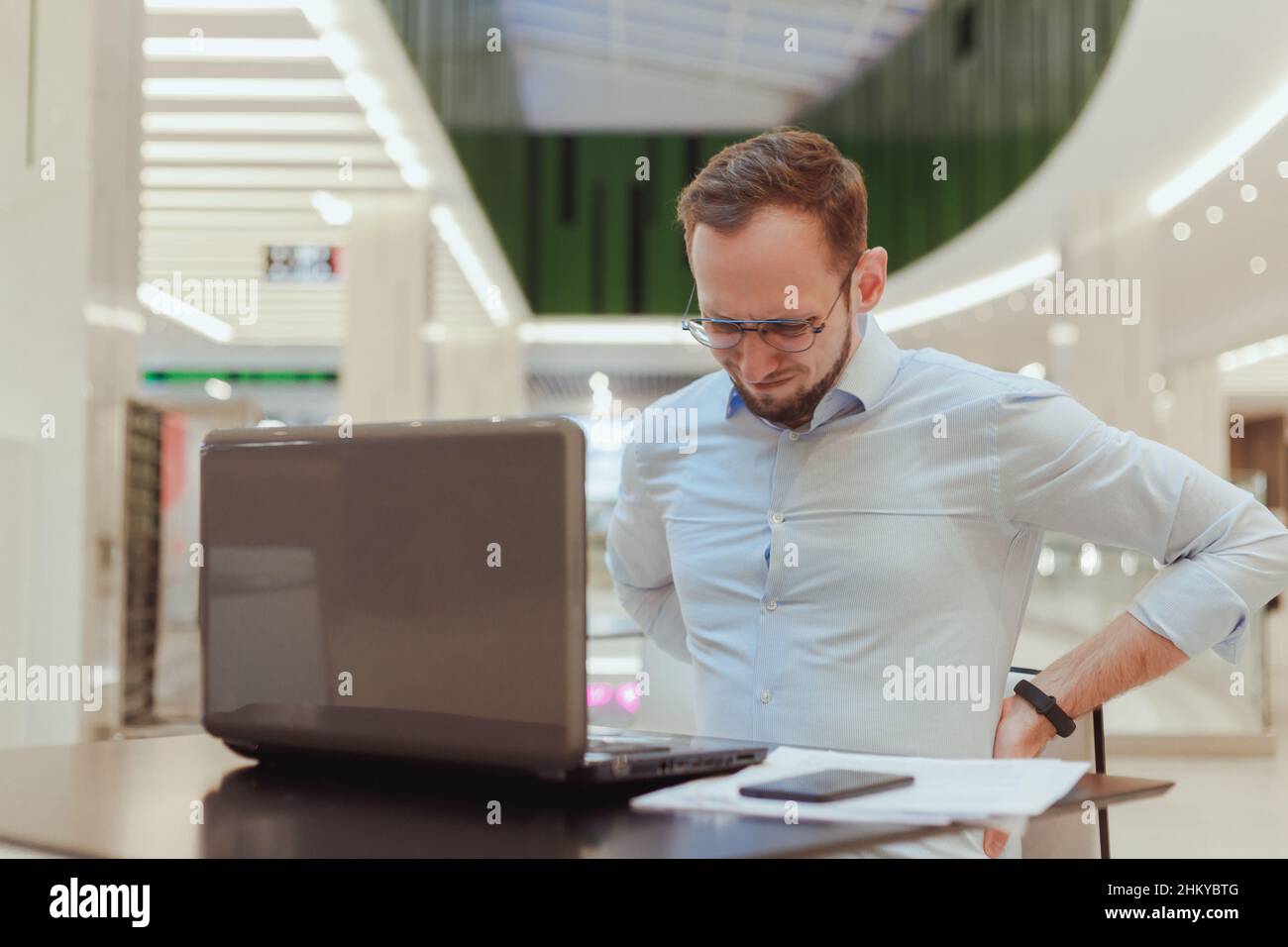 Man holds on to his back, suffers from lower back pain, working on ...
