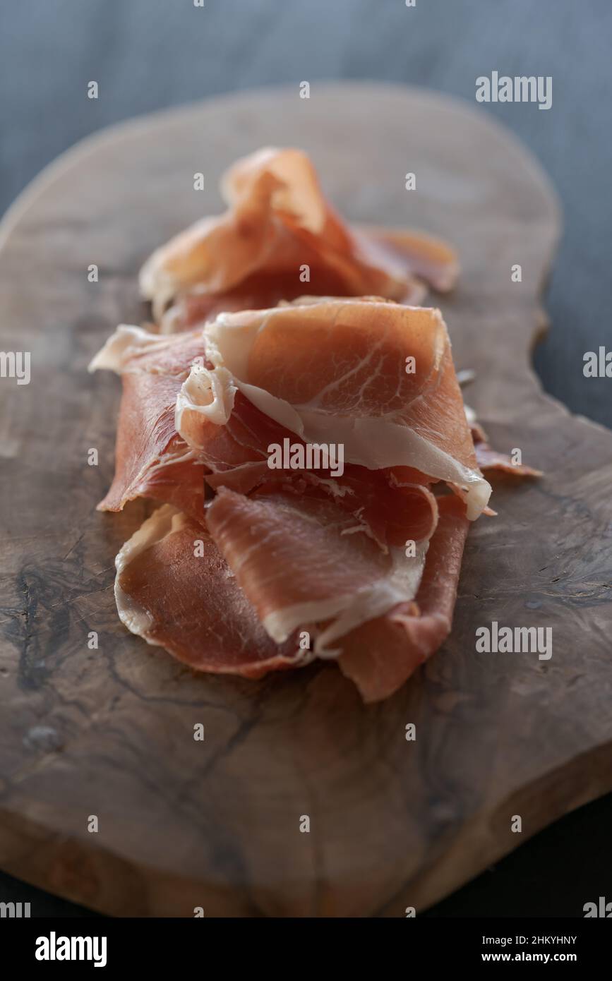 Thin slices of jamon on olive wood board, minimalist photo Stock Photo ...
