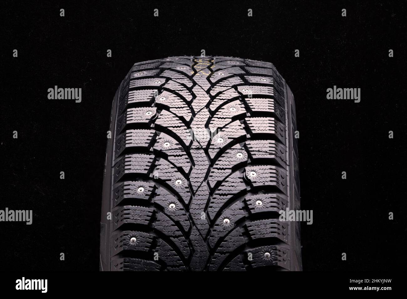 winter studded tire front view close-up on a black background tread ...