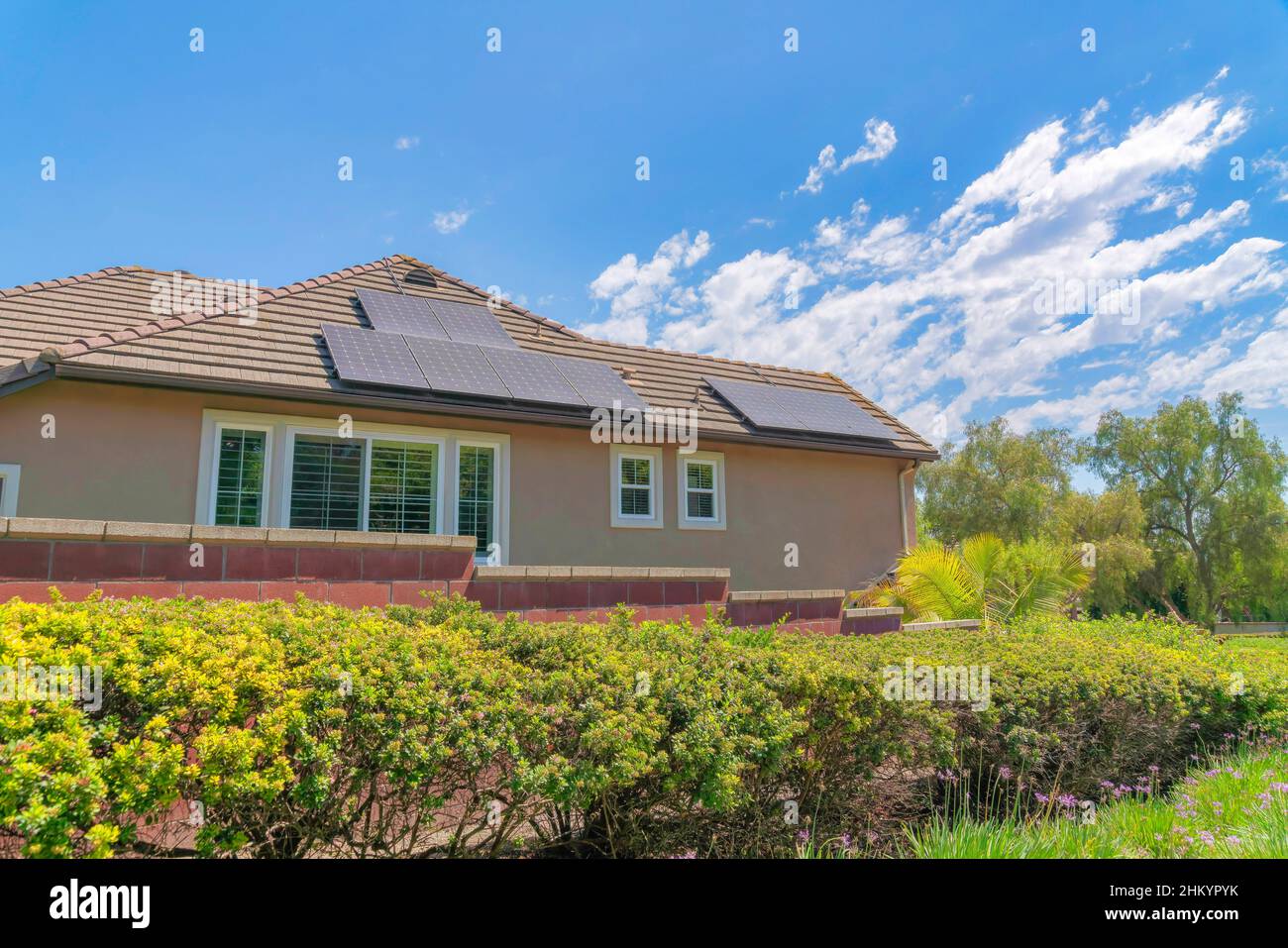 Exterior of a light brown house with solar panels on the shingles roof ...