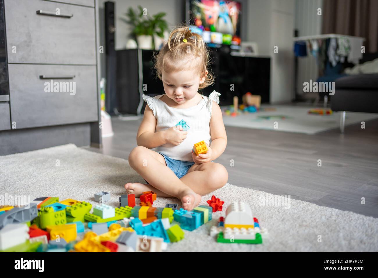 Caucasian child a little girl is playing in the constructor at home ...