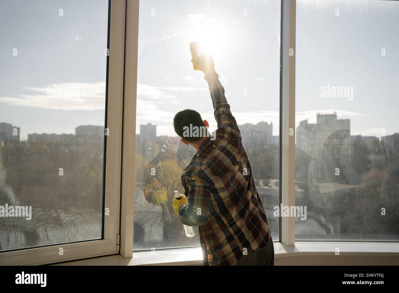 man washing windows at home, casual wear shirt, yellow rubber gloves ...