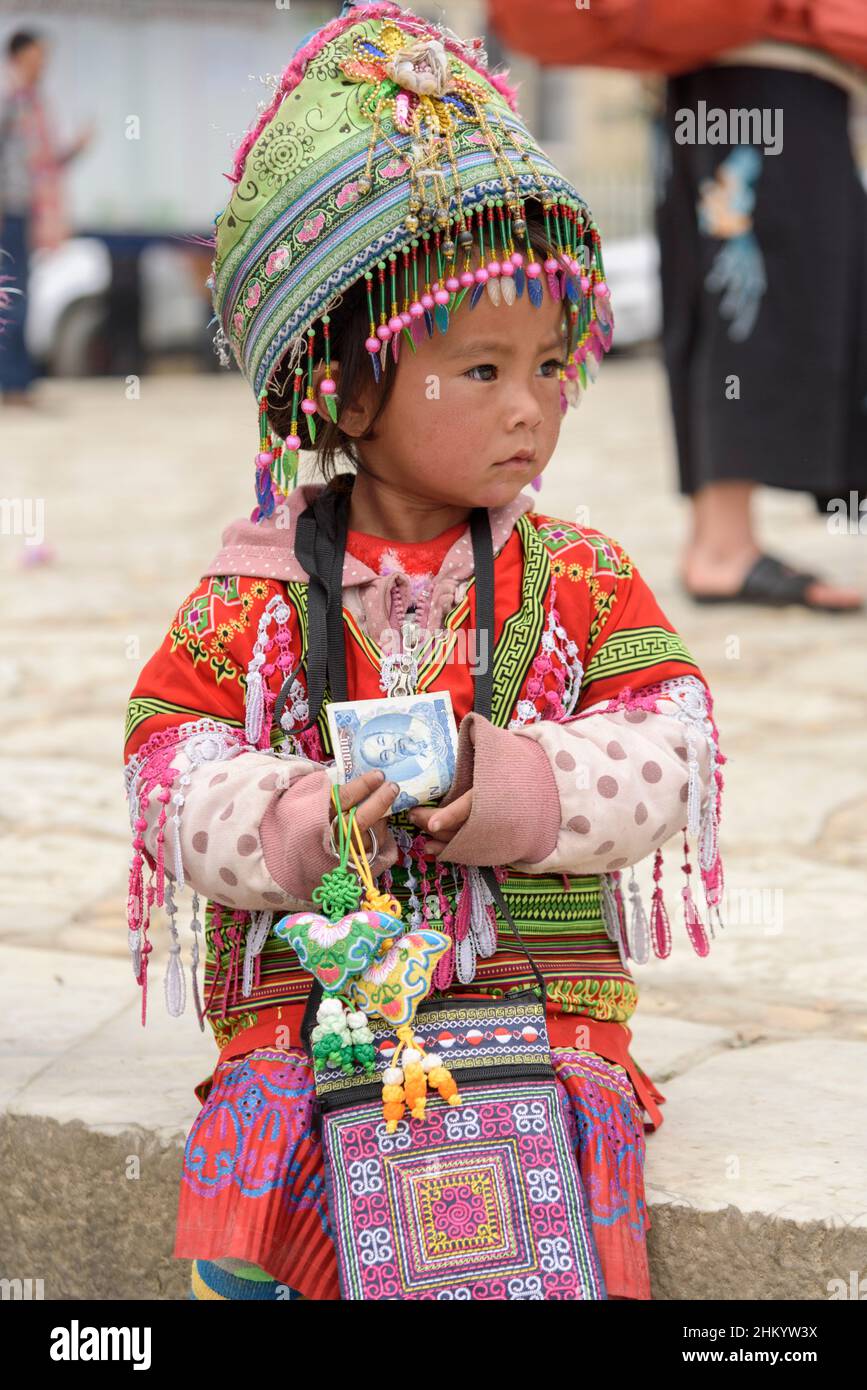 A young girl, wearing traditional Hmong tribe clothing, collects money ...