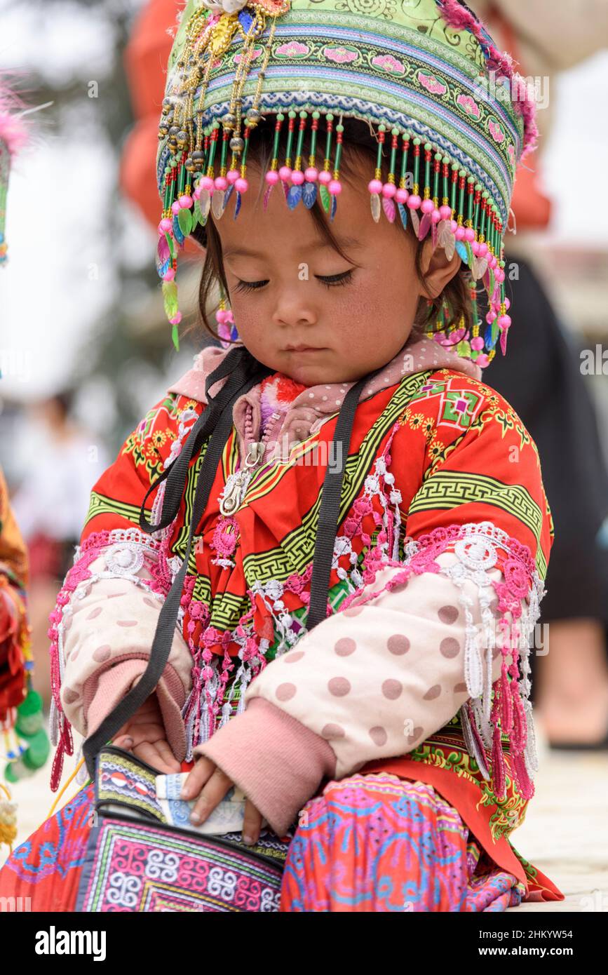 A young girl, wearing traditional Hmong tribe clothing, collects money ...