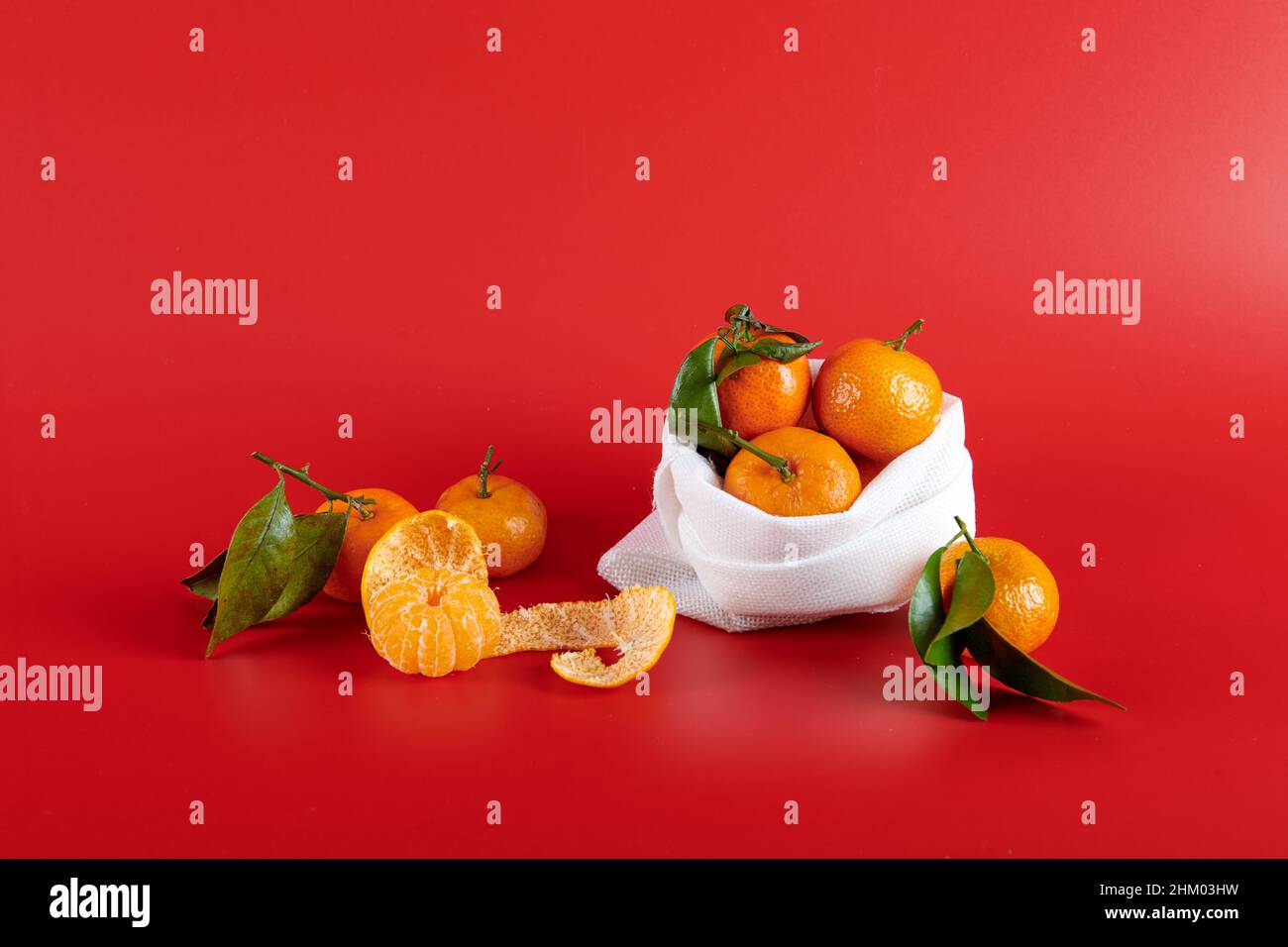 bag with orange tangerines on a red background Stock Photo - Alamy