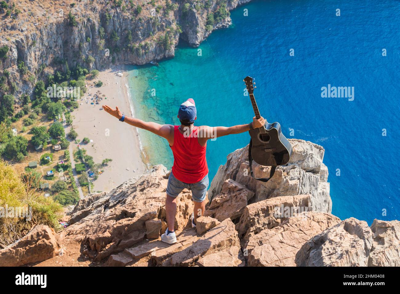 Musician man standing and holding guitar with open arms at the edge of ...