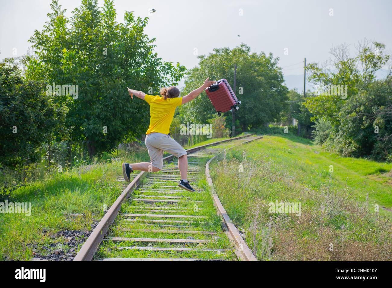 perky man with a suitcase jumping on the railroad Stock Photo - Alamy