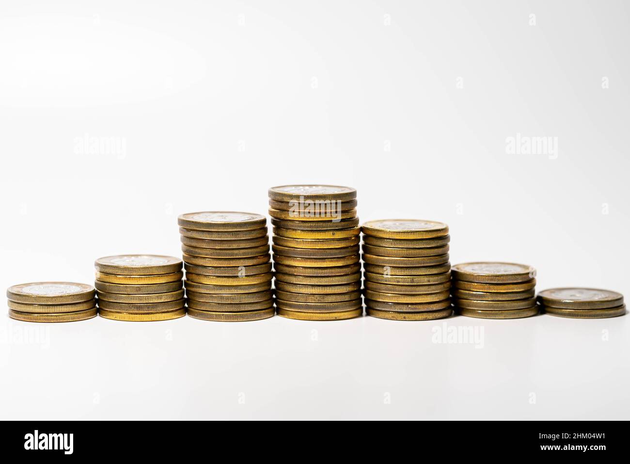 Increasing and decreasing pile of coins going up close up on white ...