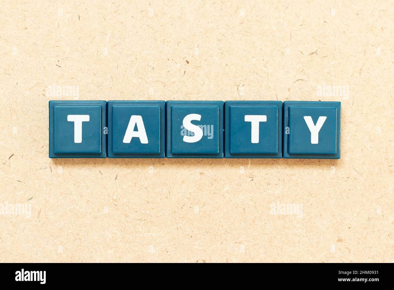 Tile alphabet letter in word tasty on wood background Stock Photo - Alamy