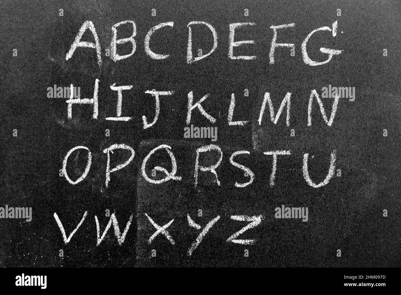 White color chalk hand drawing in english capital letter shape on black ...