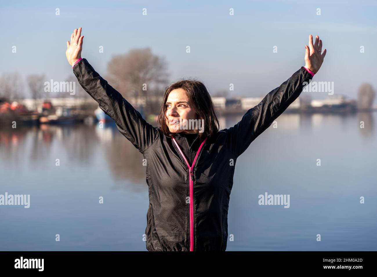 young female runner is putting her hands up on the quayside in the ...