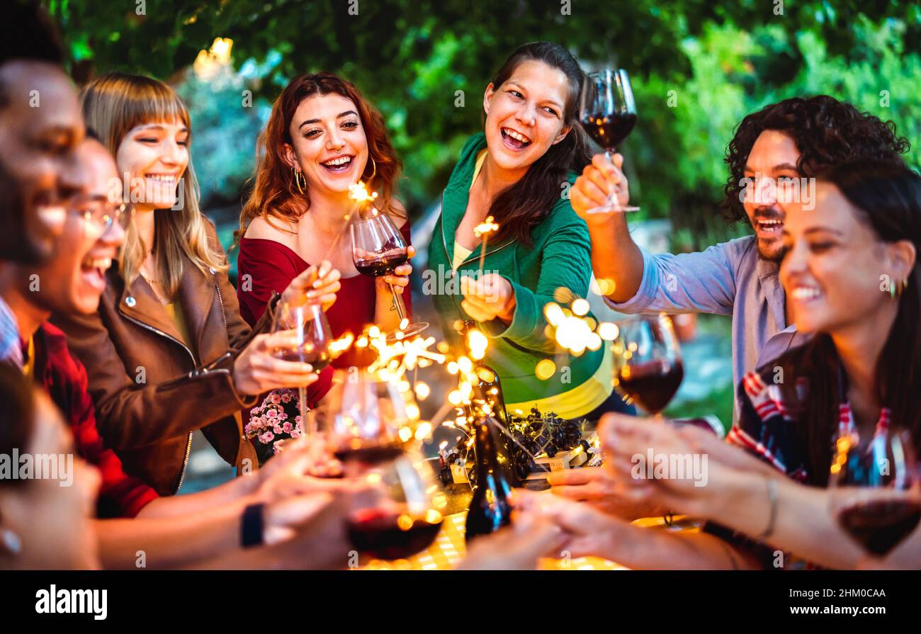Happy friends having fun with fire sparkles while toasting red wine ...