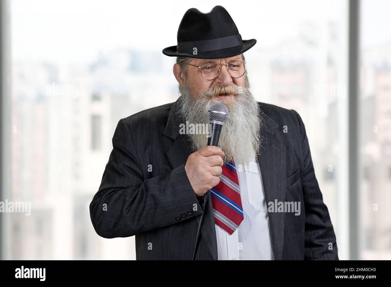 Senior bearded man wearing classic suit talking into microphone. Man ...