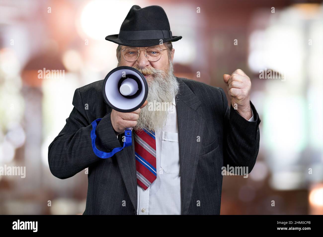 Senior man politician talking into megaphone and holding his fist ...