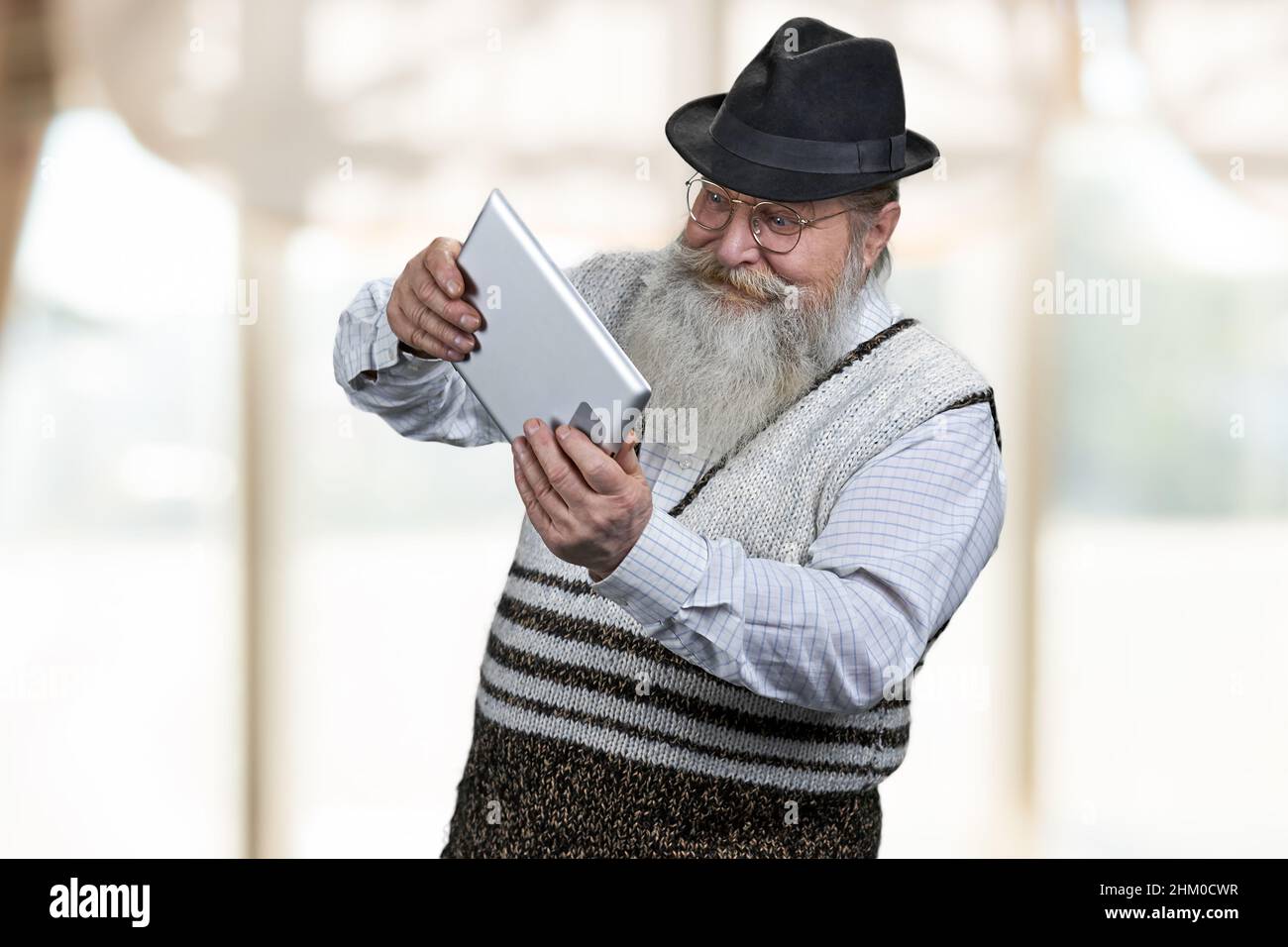 Enthusiastic senior man playing online game using digital tablet. Old ...
