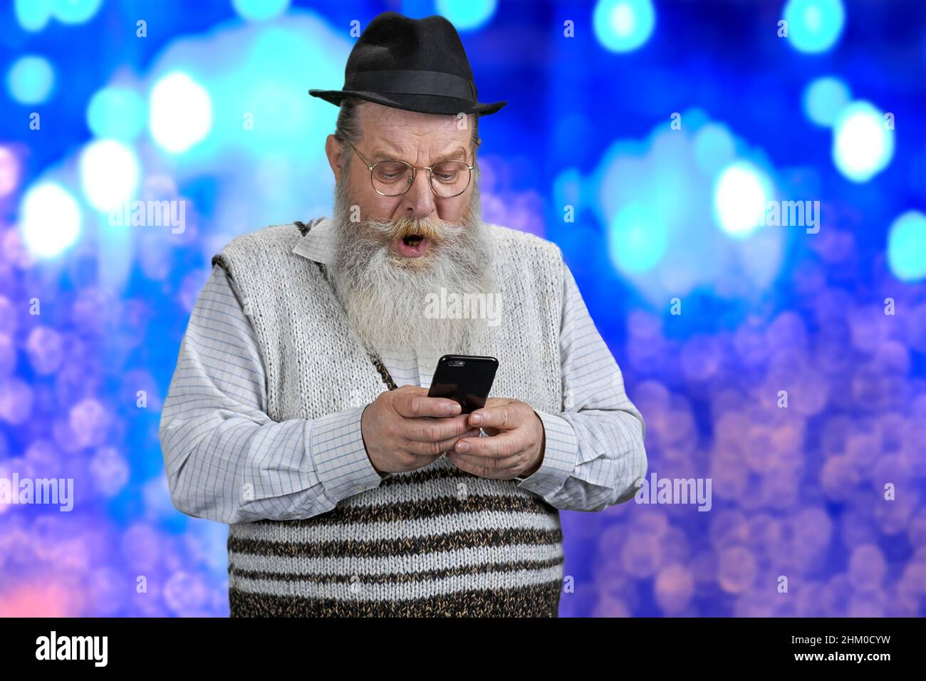 Portrait of stunned senior man surfing internet on mobile phone ...