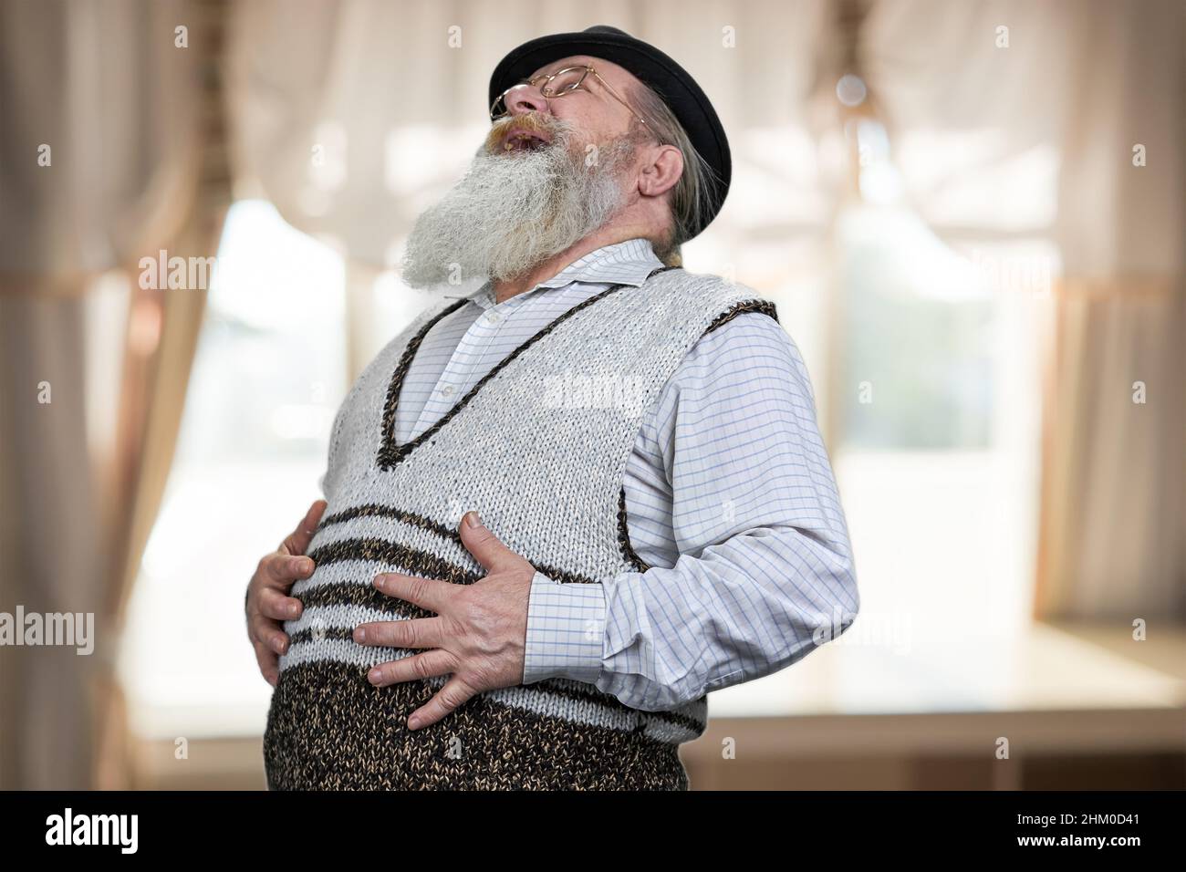 Old bearded man is lauging and touching his belly. Funny grandfather is ...