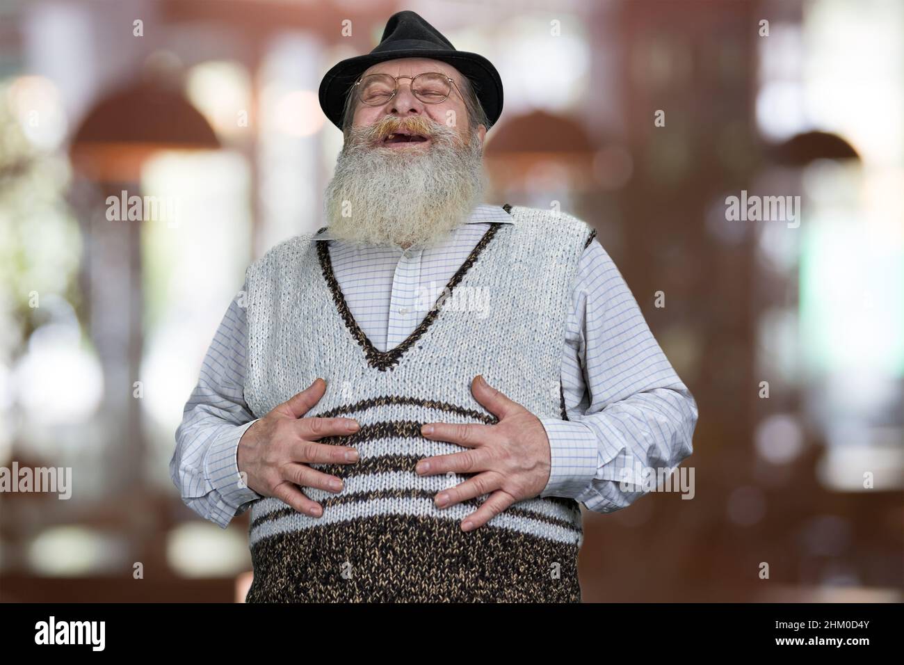 Old retired man laughing heartily out loud on blur interior background ...