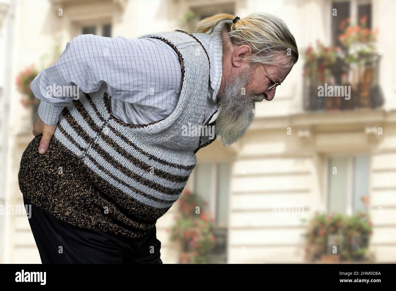 Old man suffering from sudden backache standing outdoors. City ...