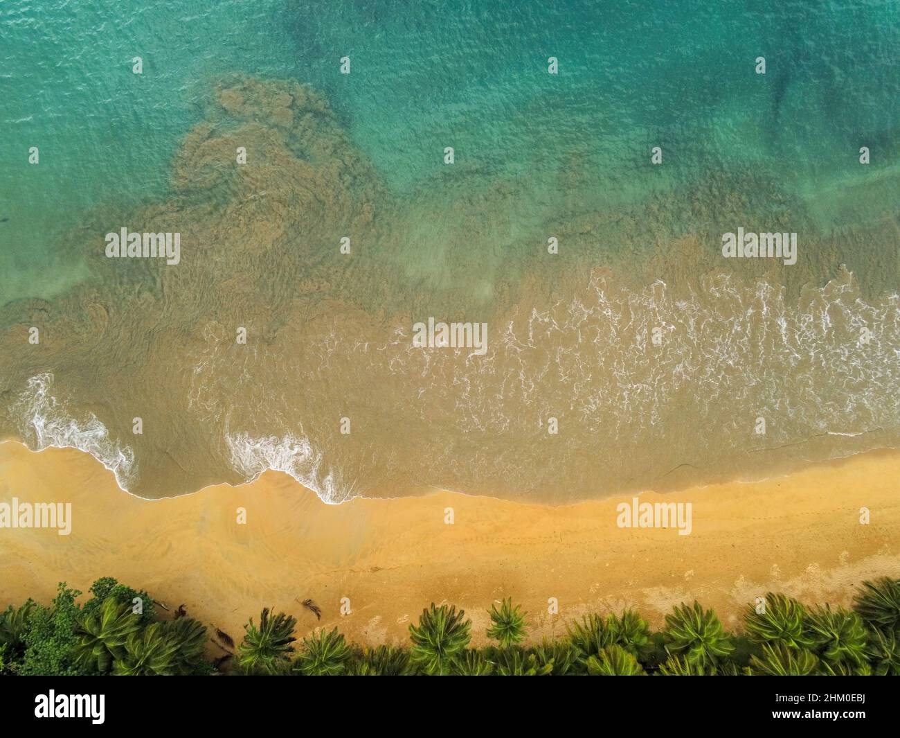 Top view of the teal water of the ocean washing the shore in Sao Tome e ...