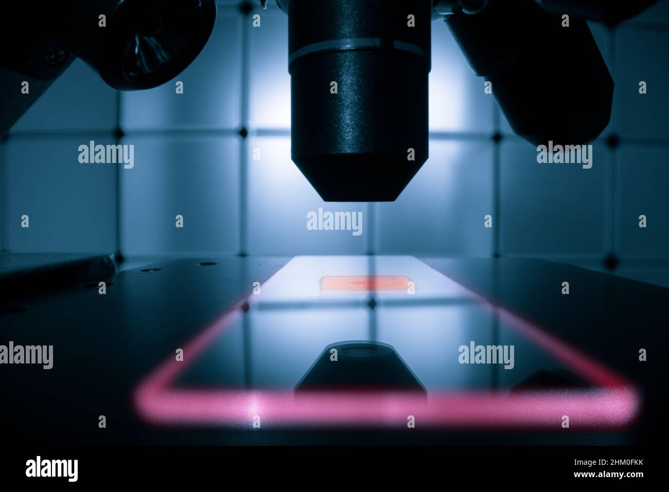 microscope table with a luminous slide and a microscope lens on a dark ...