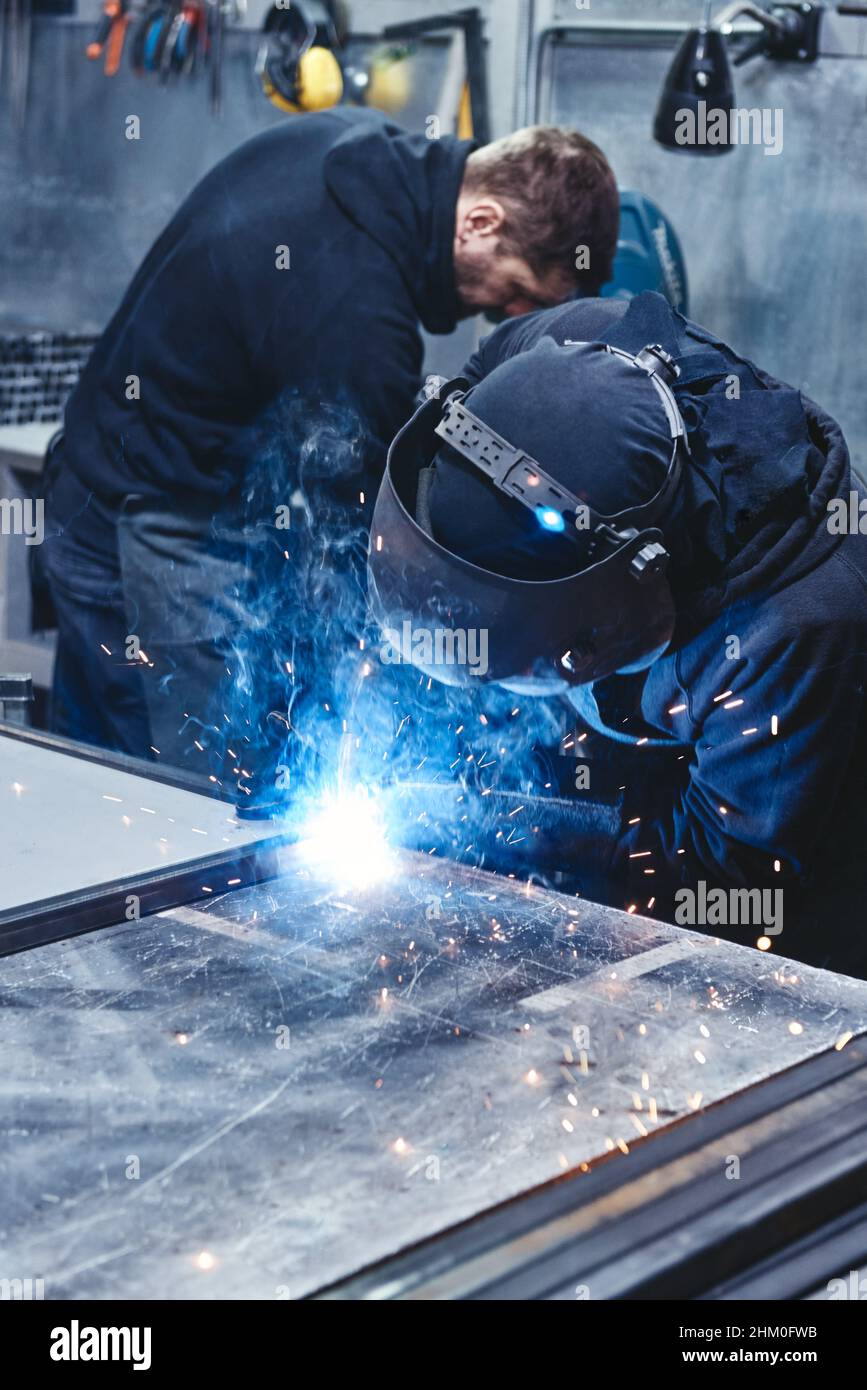 Industrial worker wearing helmet and gloves welding steel construction ...