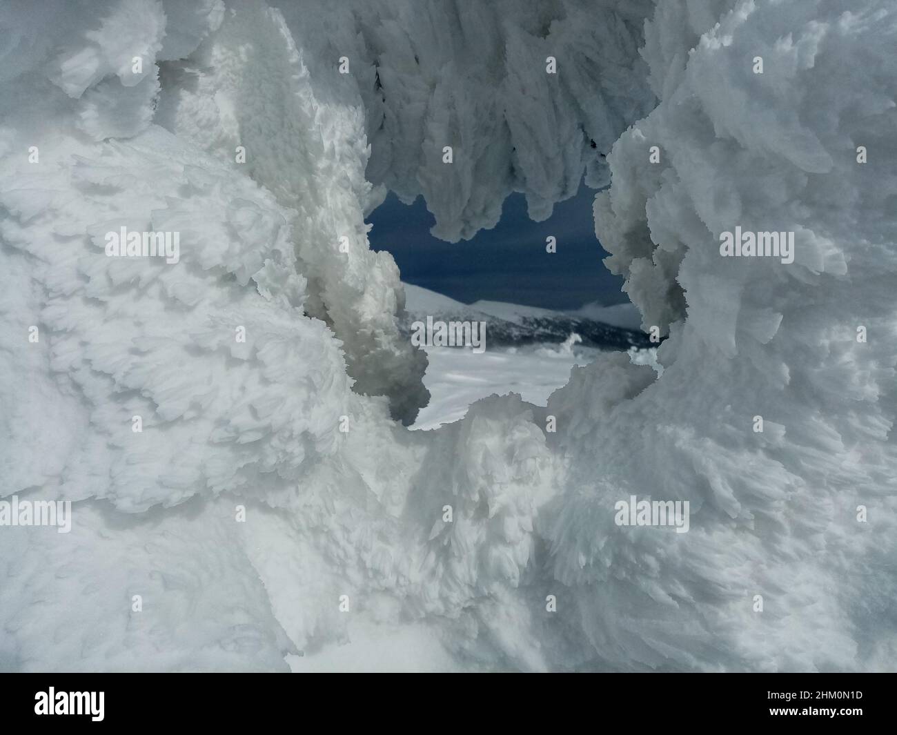 A hole in a freezing block through which you can see a distant mountain ...