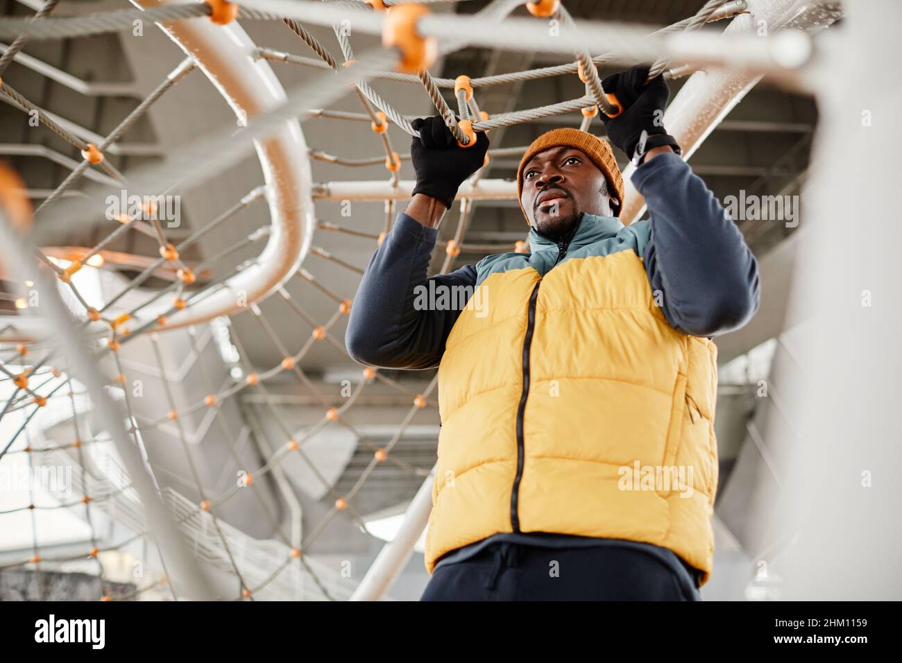 Young African American sportsman in warm sports clothes pulling up on ...