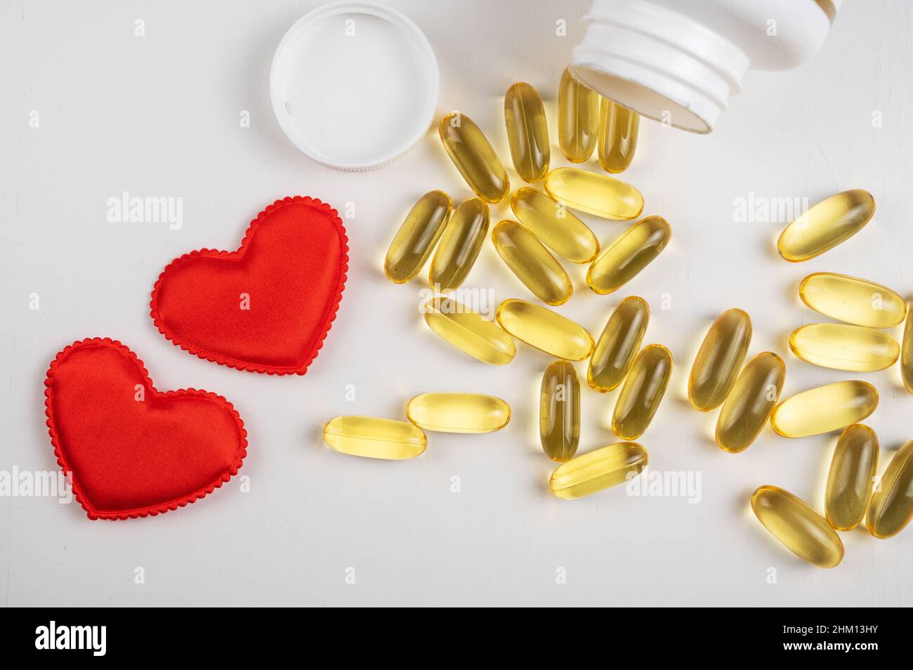 Gold fish oil isolated on white background with red hearts. Pile of ...
